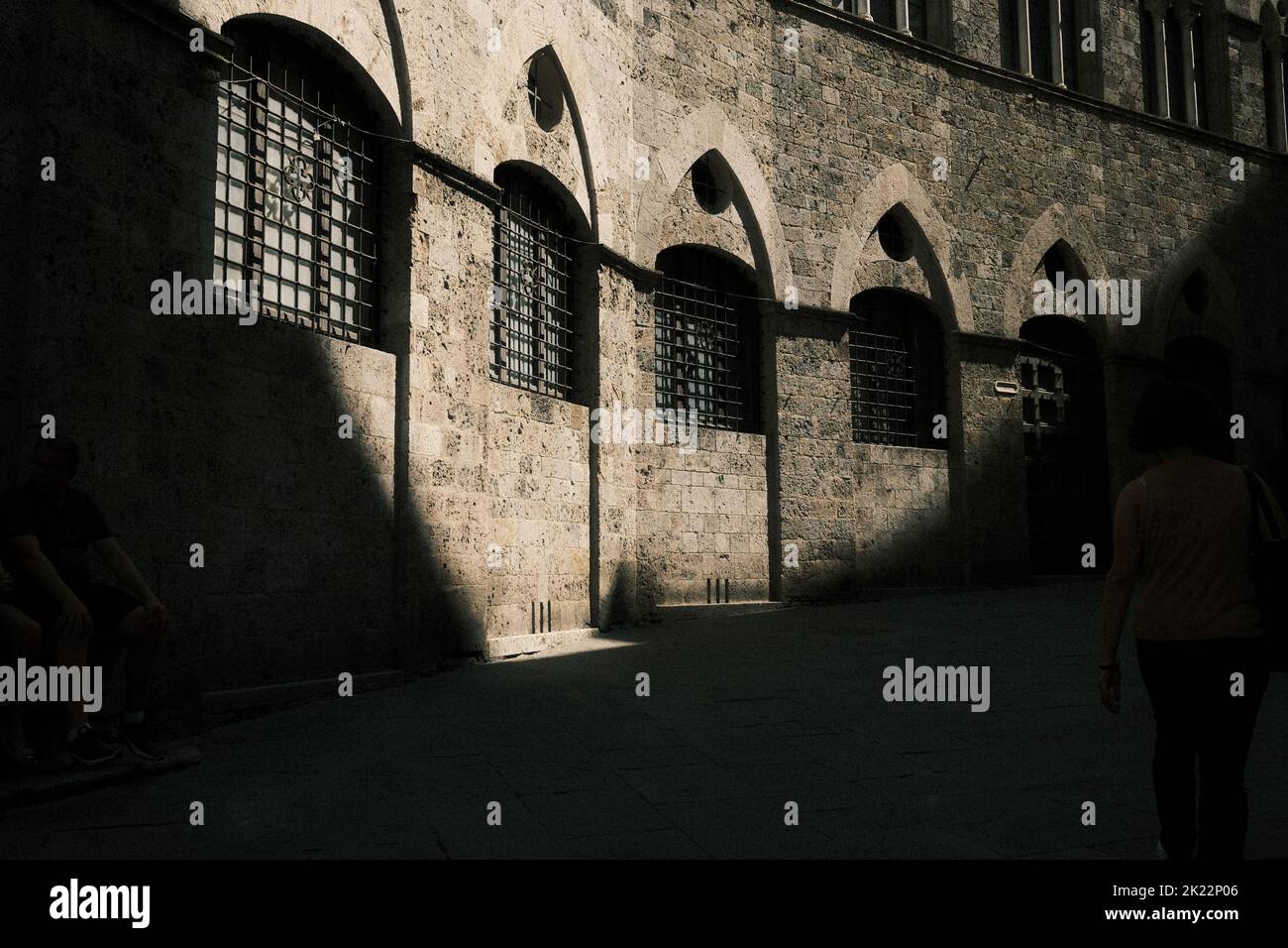 An ancient gray-stoned building with windows in Gothic style with the ...