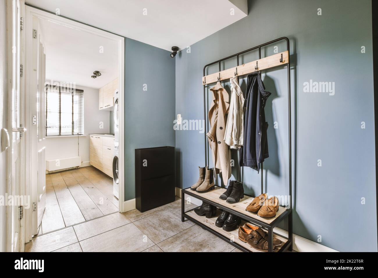 Narrow corridor with blue walls and doors leading to spacious room with ...