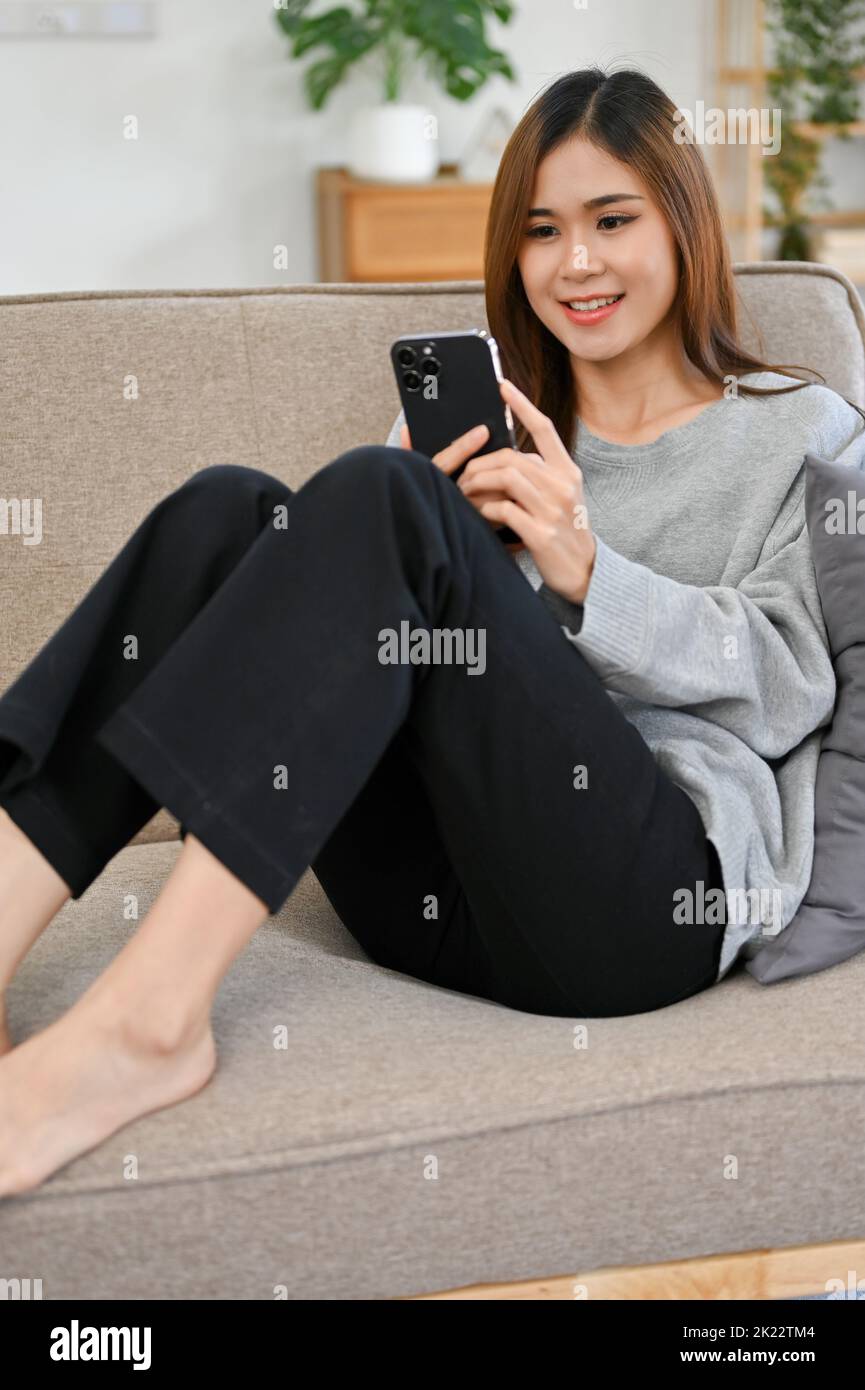 Pretty and charming young Asian female in casual outfit stay at home on ...