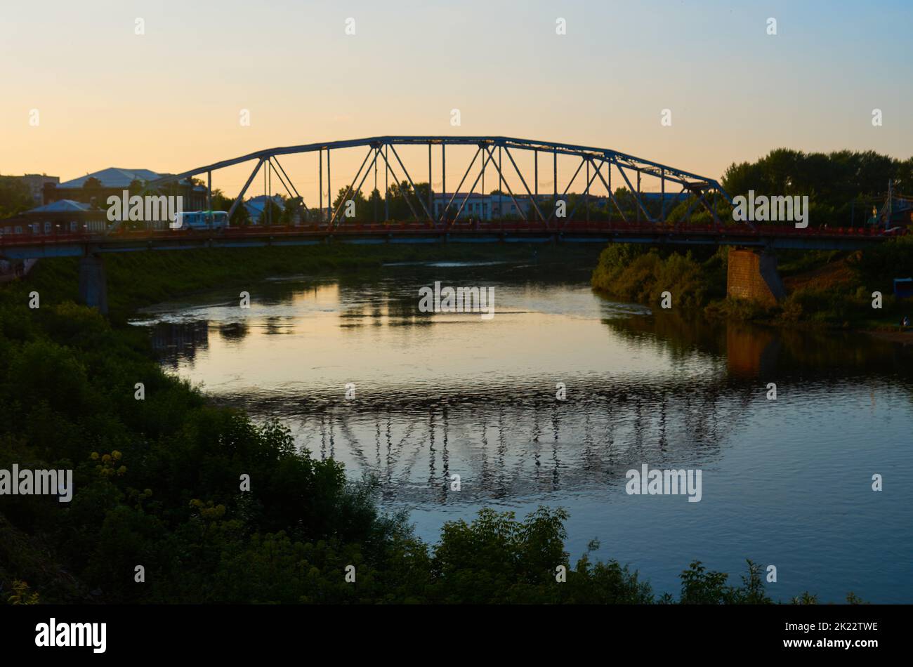 View of small steel bridge over the river or lake with dense coniferous ...