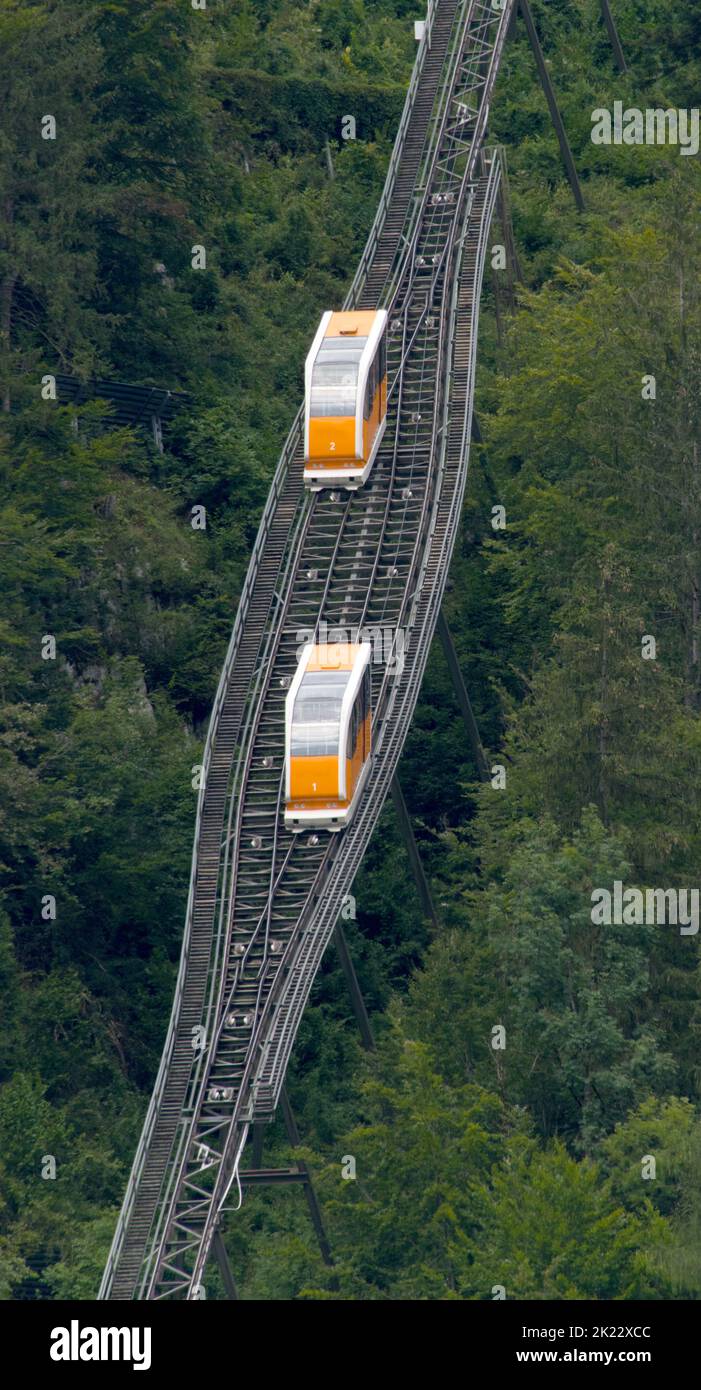 Two orange cars of rack cog railroad meeting and passing by in green ...