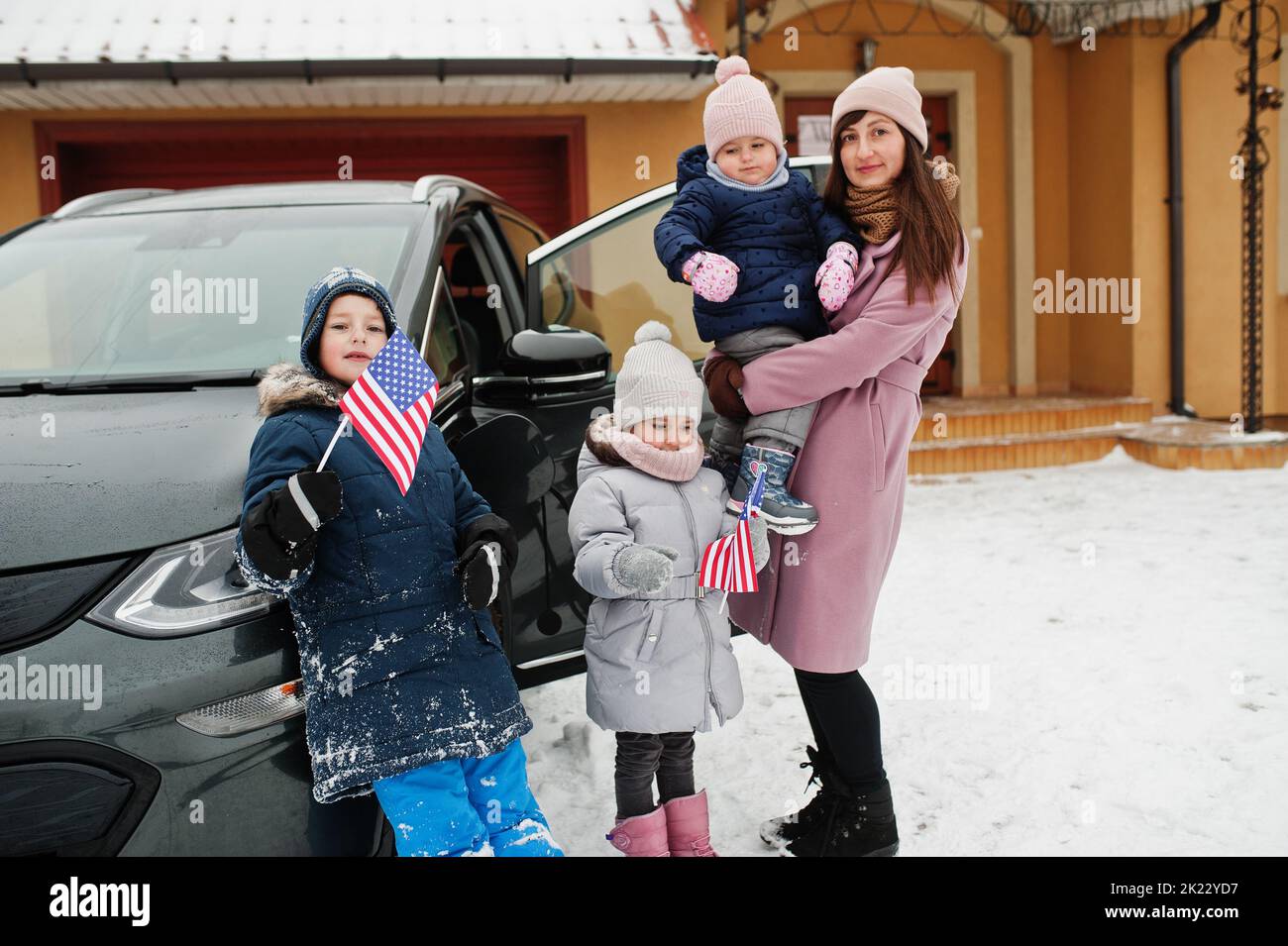 Young american mother with kids hold USA flags and charging electric ...