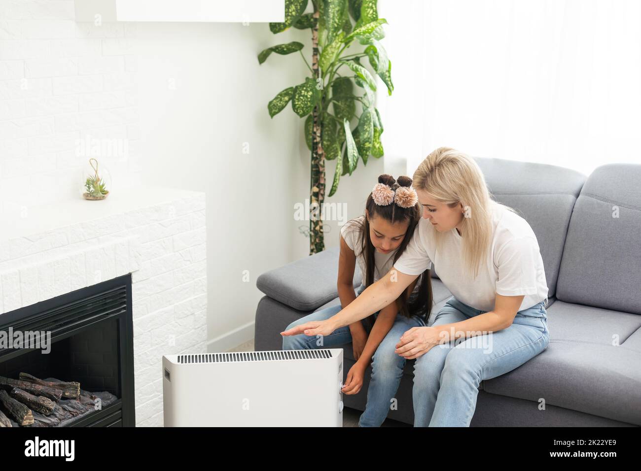 Mother and child warming hands near electric heater at home Stock Photo ...