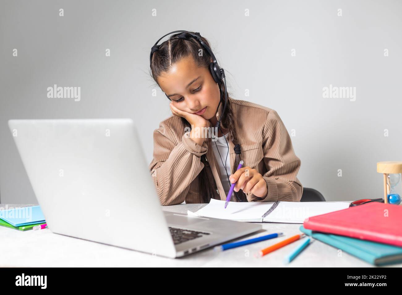 Tired schooler child girl at home with laptop for remote connection ...