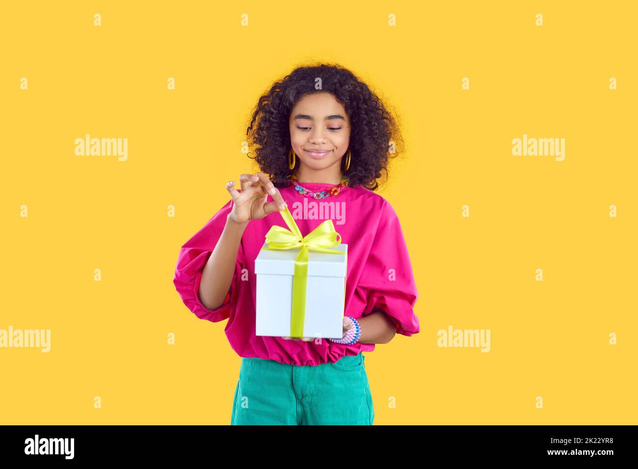 Happy little child receives a birthday present and unties the bow on ...