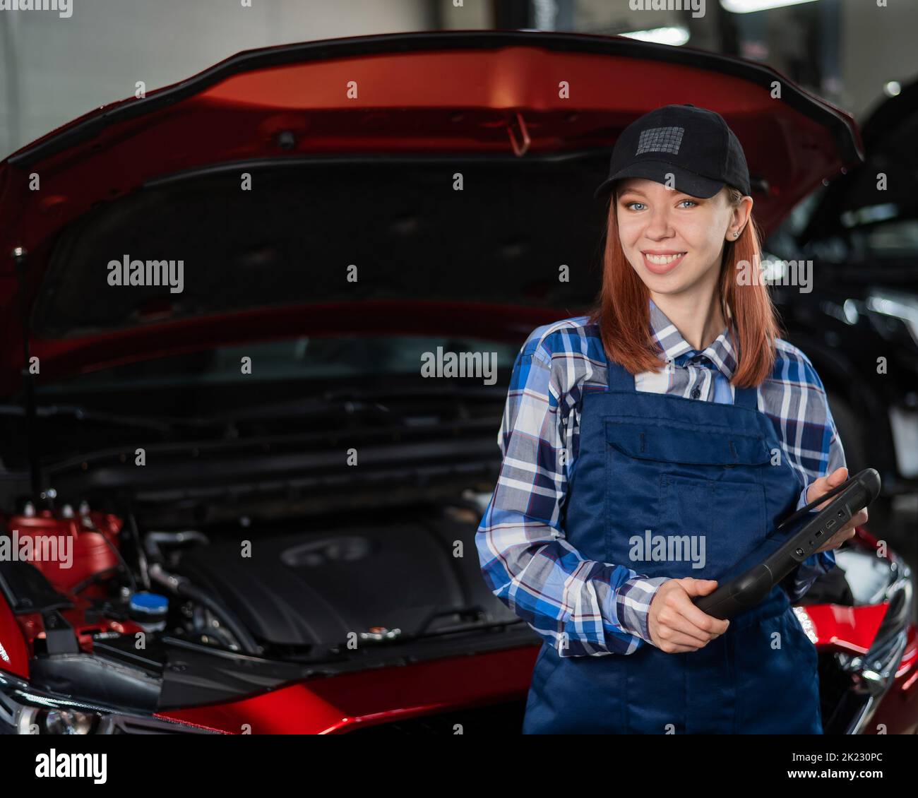 Caucasian female auto mechanic uses a special computer to diagnose ...