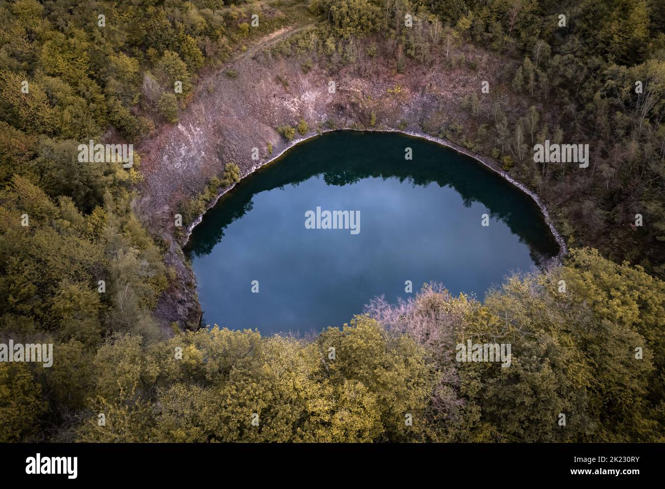 Small blue crater lake of a dormant volcano surrounded by forest in ...
