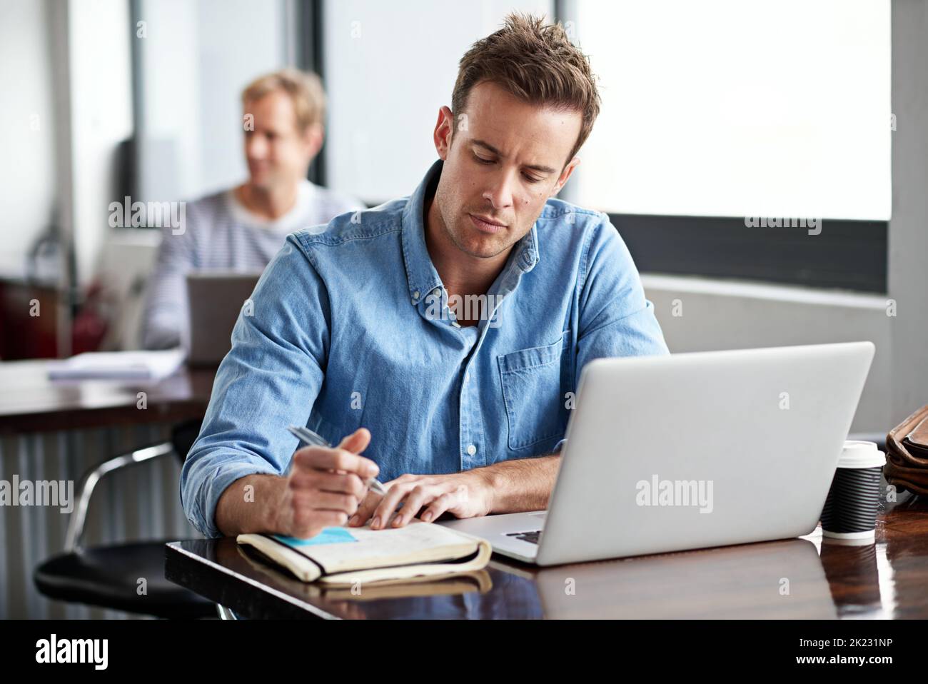 Bringing his ideas to life. a man writing notes while working on a ...