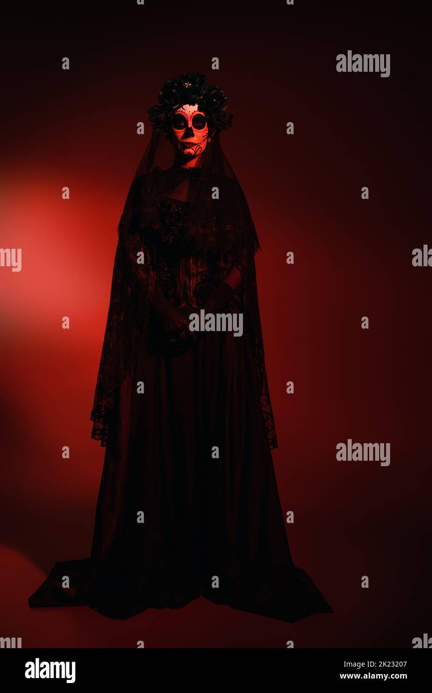 Full length of woman in mexican santa muerte costume looking at camera ...