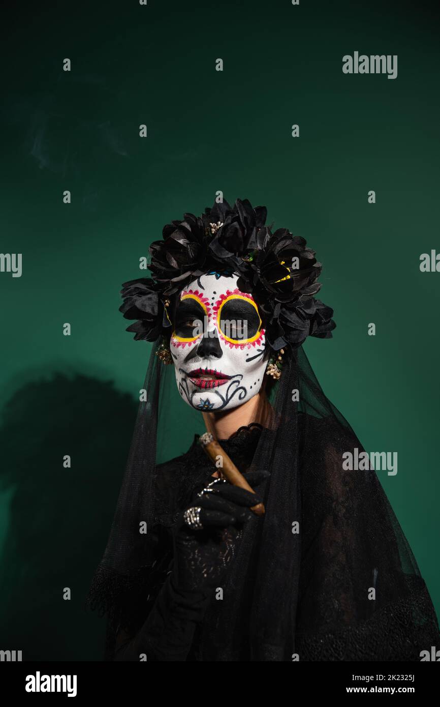 Woman in santa muerte halloween costume and wreath holding cigar on ...