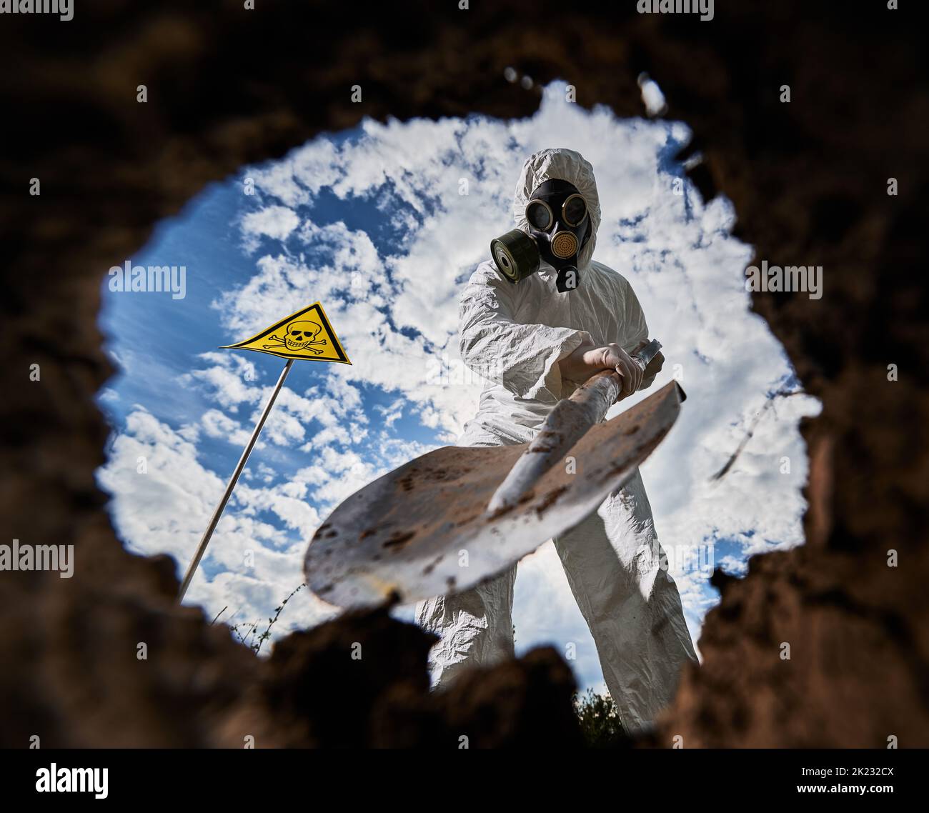 Close-up view of shovel with which scientist in gas mask digging hole ...