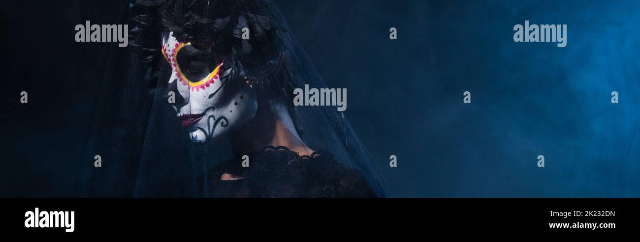 woman in catrina makeup and black wreath with veil on dark blue foggy ...