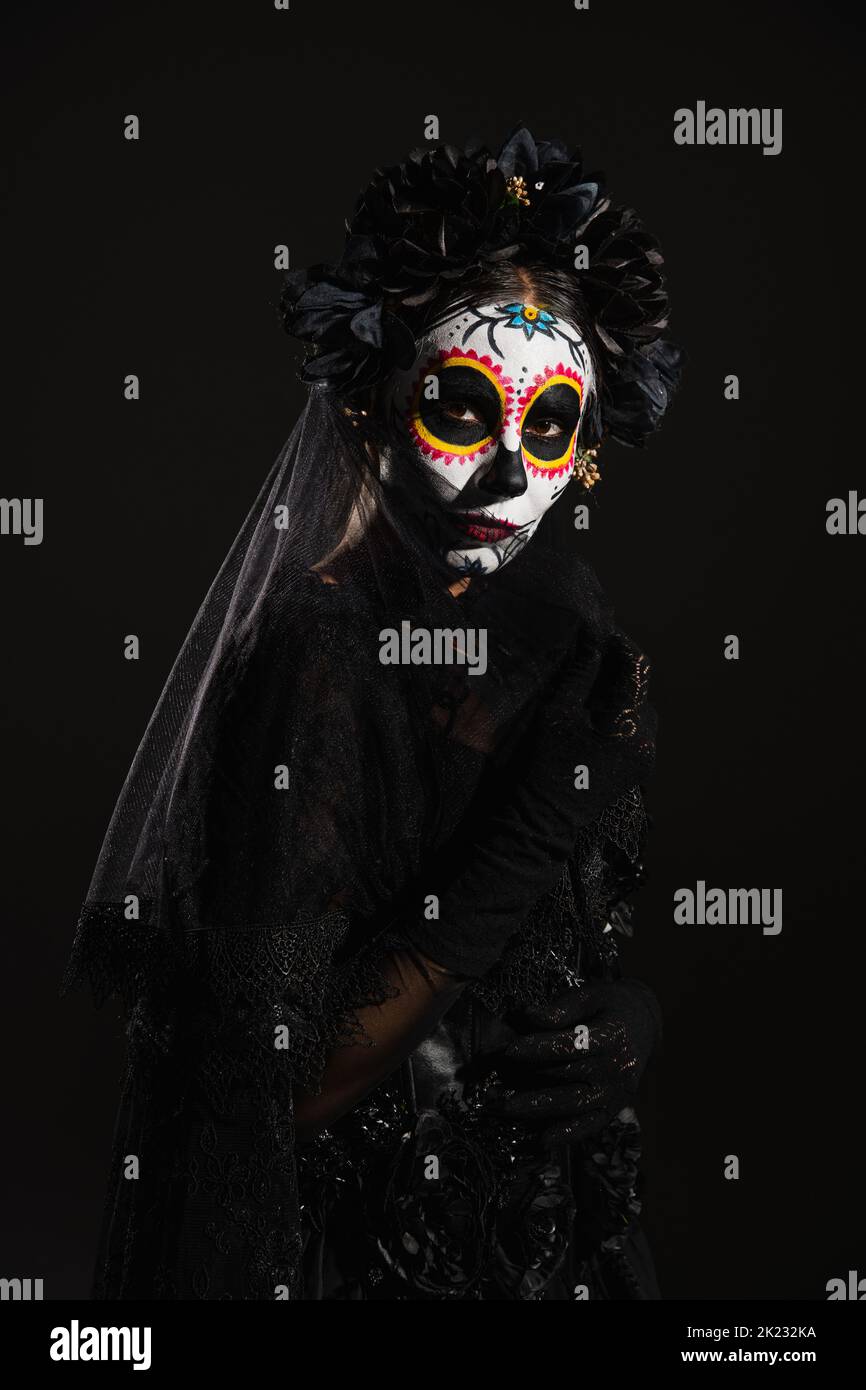 woman in traditional santa muerte makeup and dark costume with wreath ...
