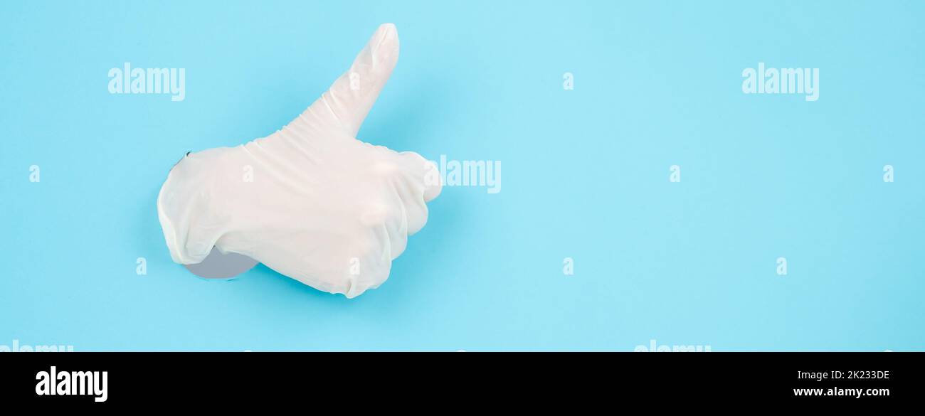 A female gloved hand sticks out through a blue paper background and ...