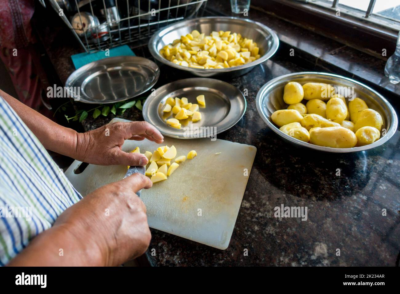 Boiled Potatoes cutting on a chopping board with visible hands and a ...