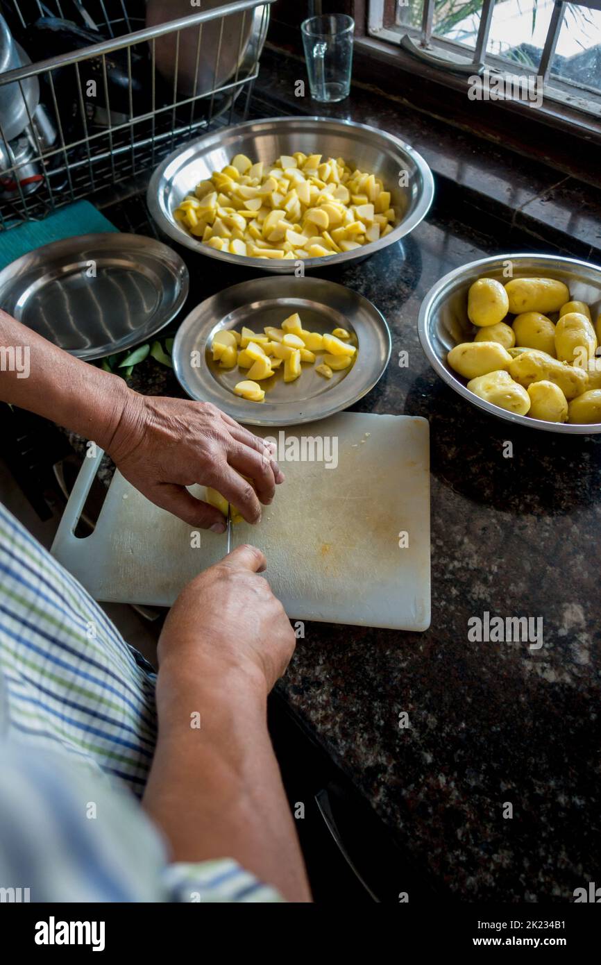 Boiled Potatoes cutting on a chopping board with visible hands and a ...