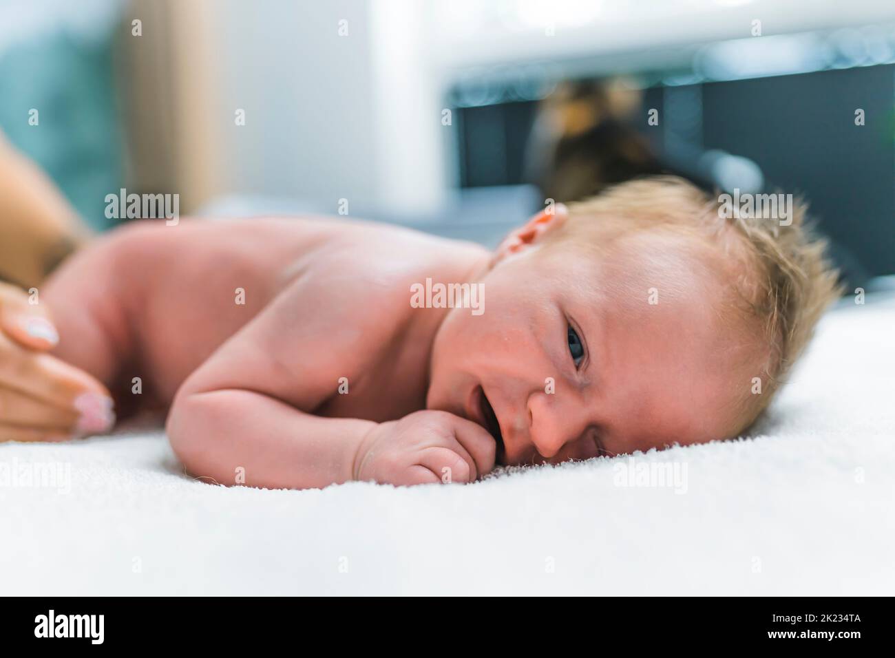 Portrait of newborn baby boy with blond hair having his diaper changed ...