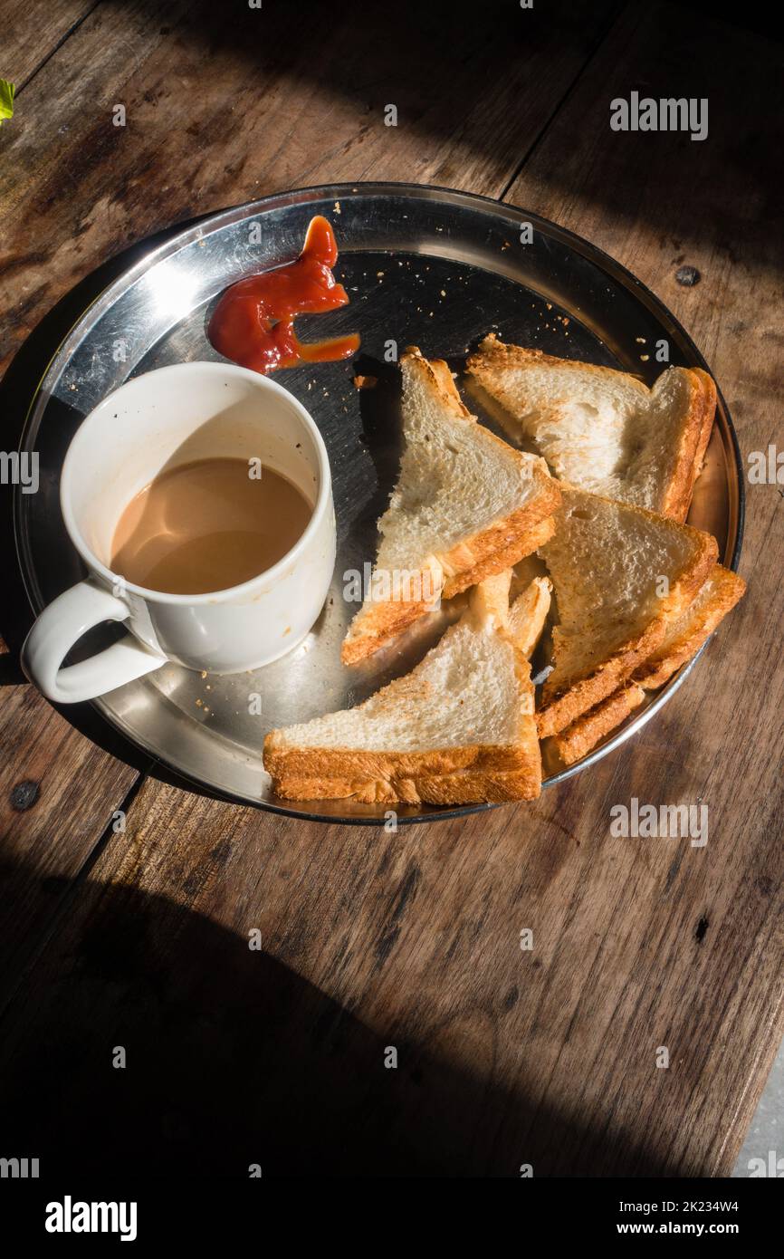 Grilled butter toast served with a cup of Indian hot tea and a tomato ...