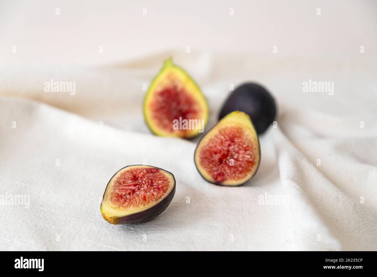 Fresh ripe and sweet figs cut and whole on beige color table cloth ...