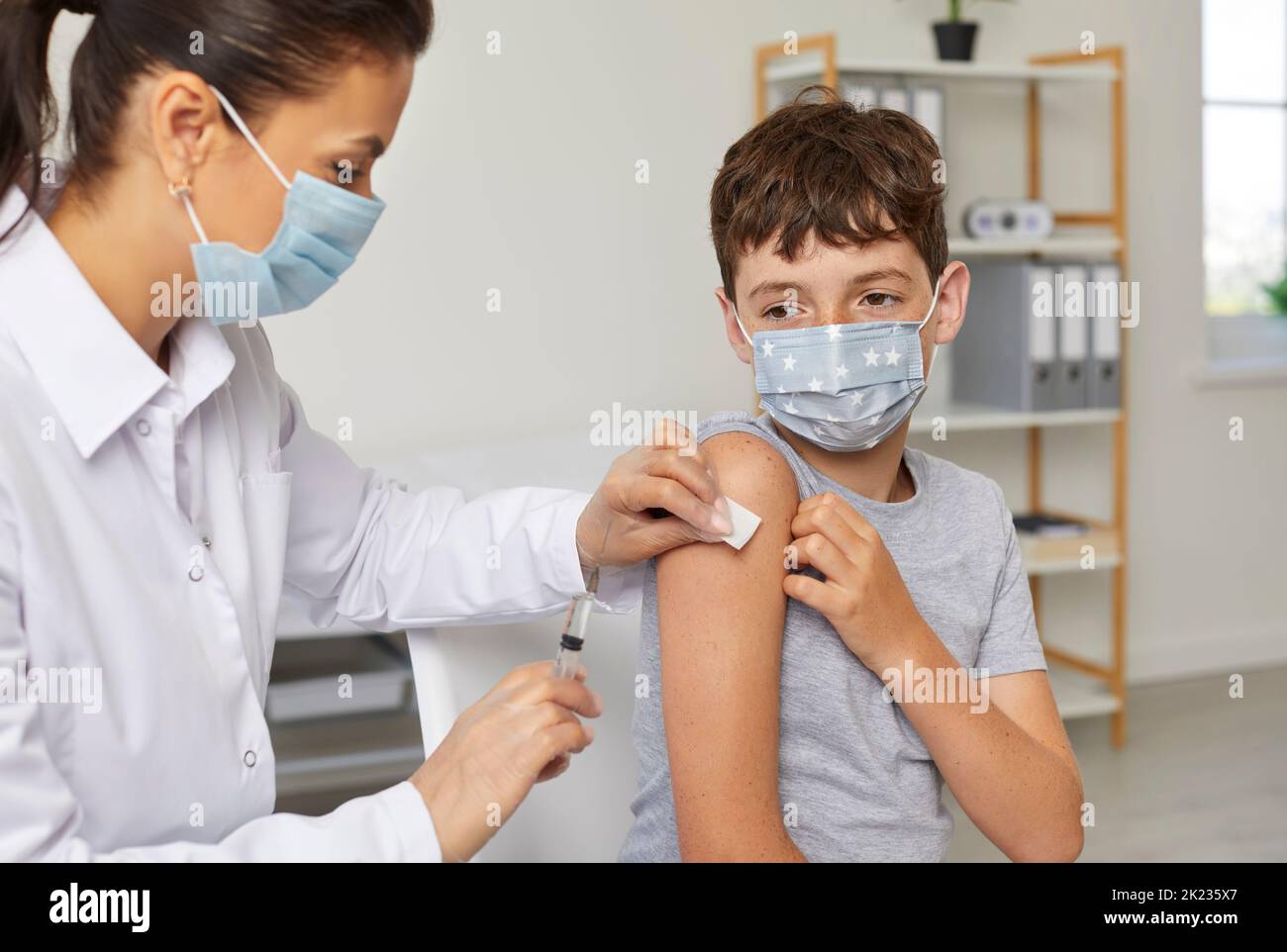 Doctor is giving a vaccine injection from flu, covid-19 to teen boy in ...