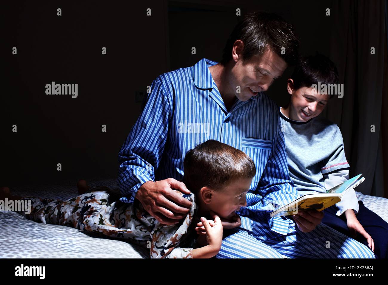 Bonding at bedtime. A father reading to his two sons at bedtime in the ...