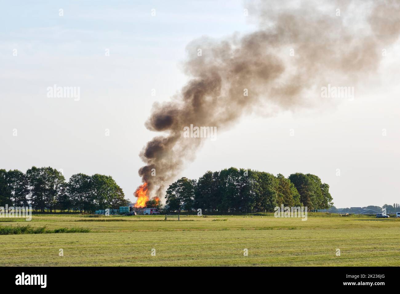 Large fire on the horizon of an agricultural field with a huge pillar ...