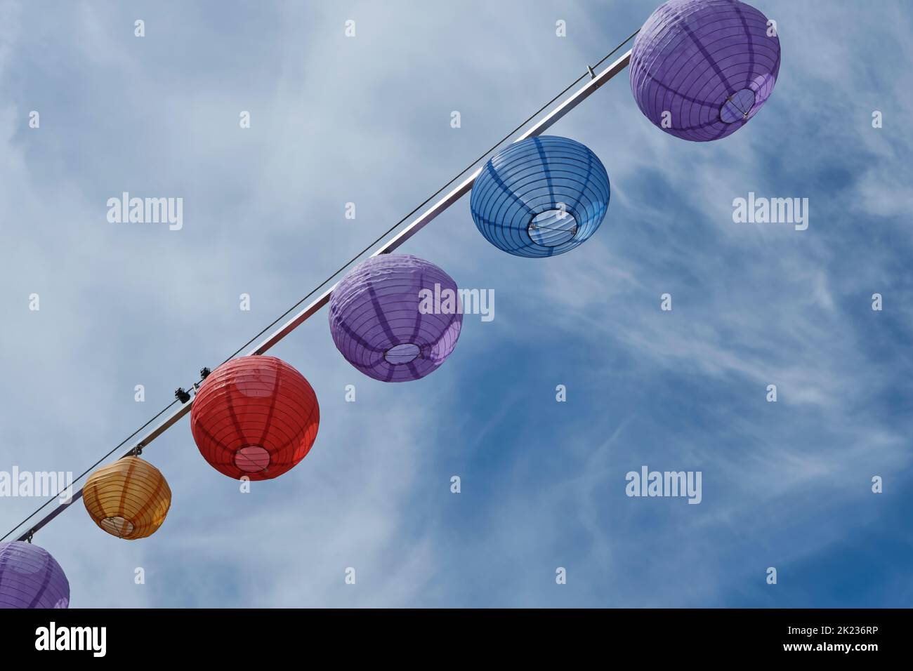 Blue, yellow, orange and red lampion or latern lamps hanging on a line ...