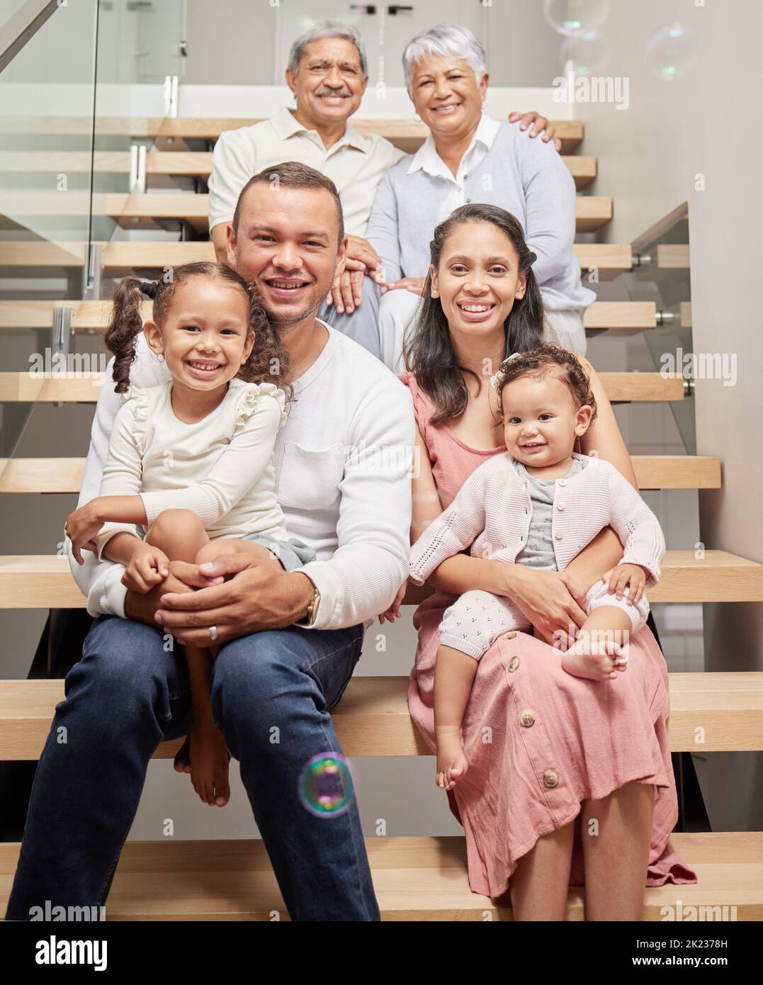 Portrait of a happy family posing for a picture on stairs in a house ...
