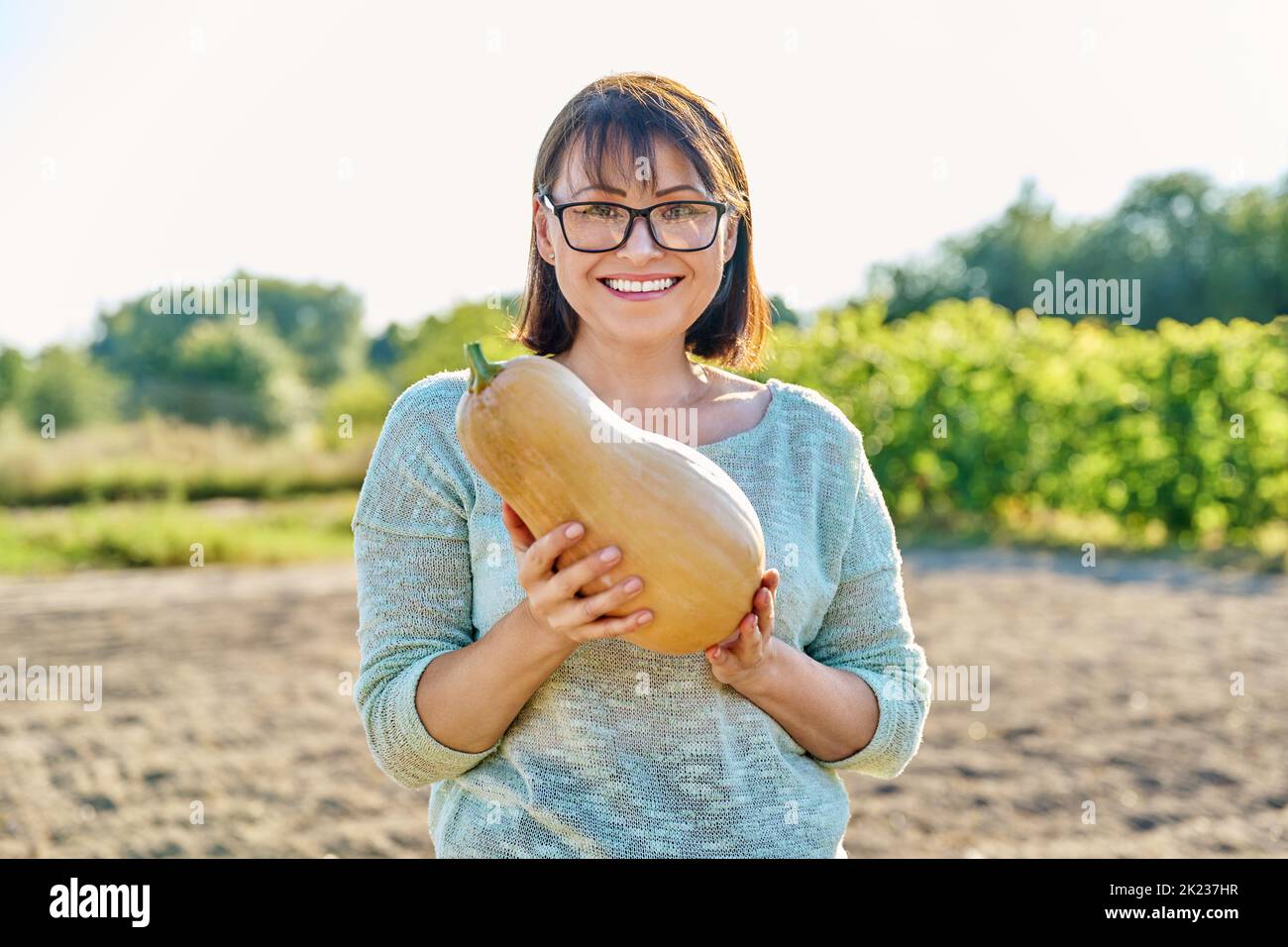 Happy woman holding ripe pumpkin at the farm, autumn season Stock Photo ...