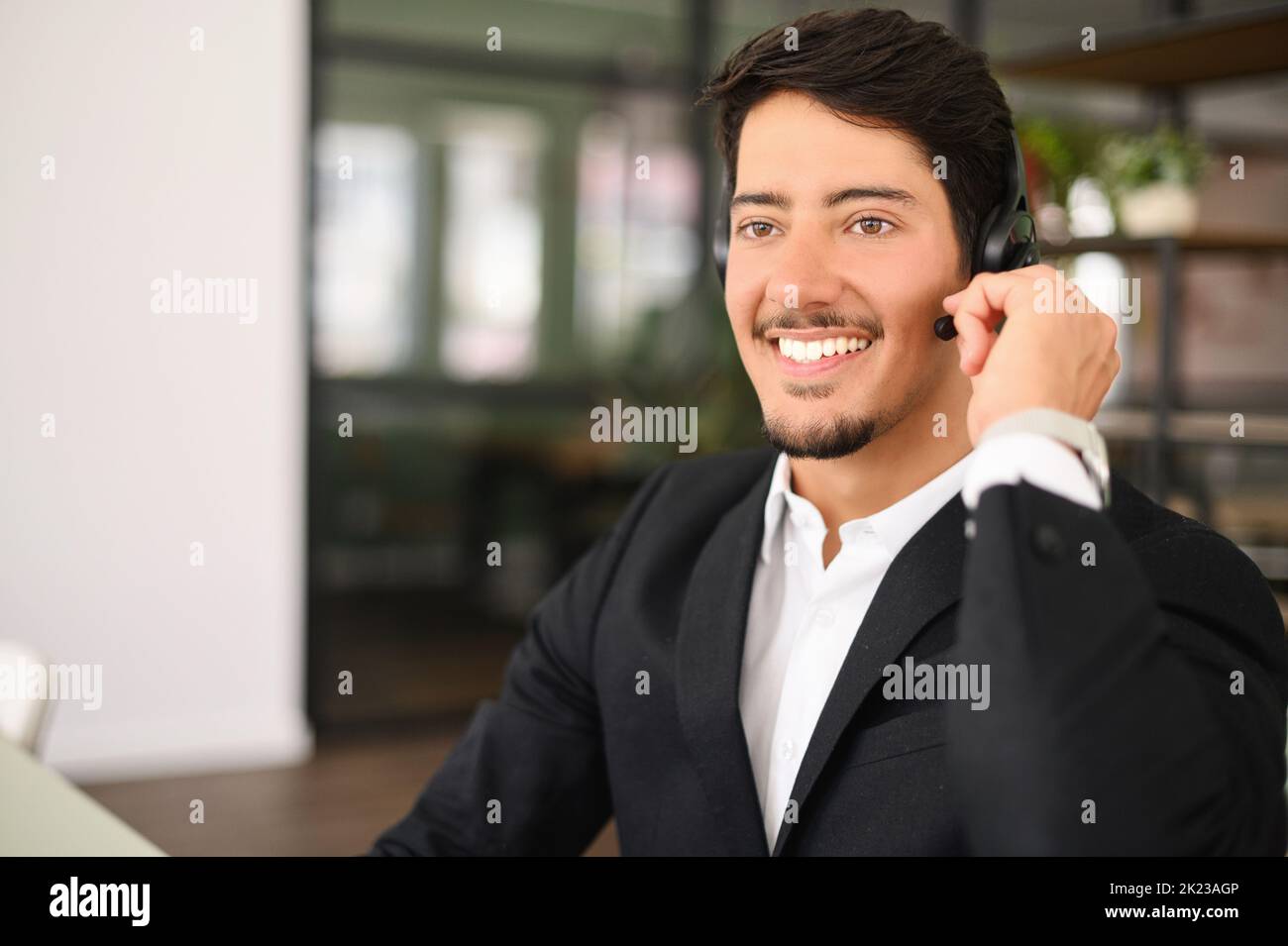 Latin young male salesman in a headset is holding the microphone, male ...
