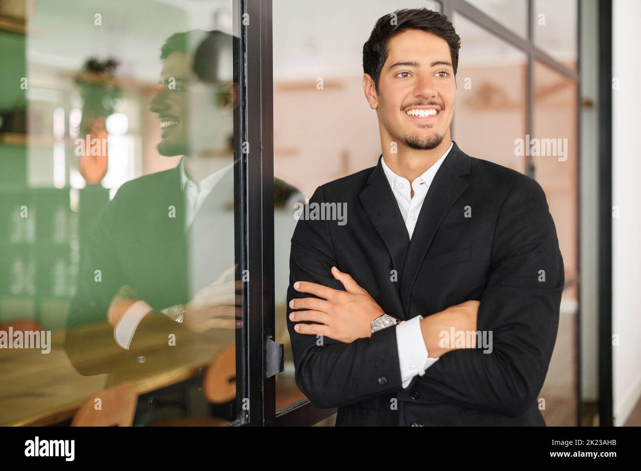 Ambitious hispanic man in formal wear stands with arms crossed in ...