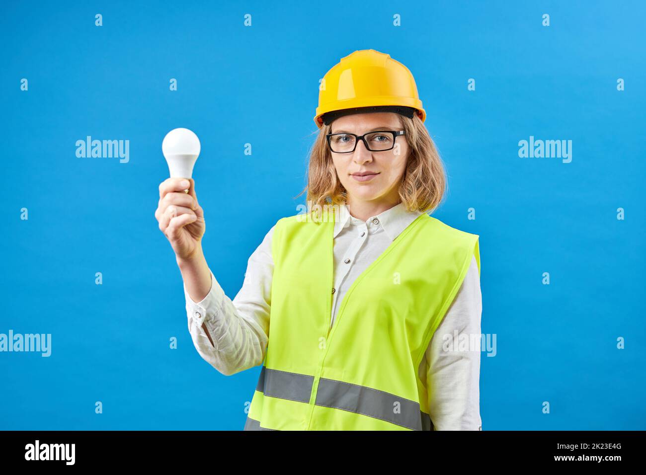 Young female engineer wearing work vest and yellow helmet on head ...