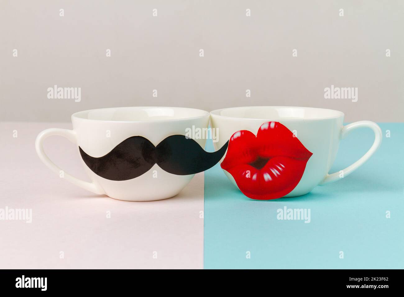 White cups decorated with moustache and lips. Love and relationship ...
