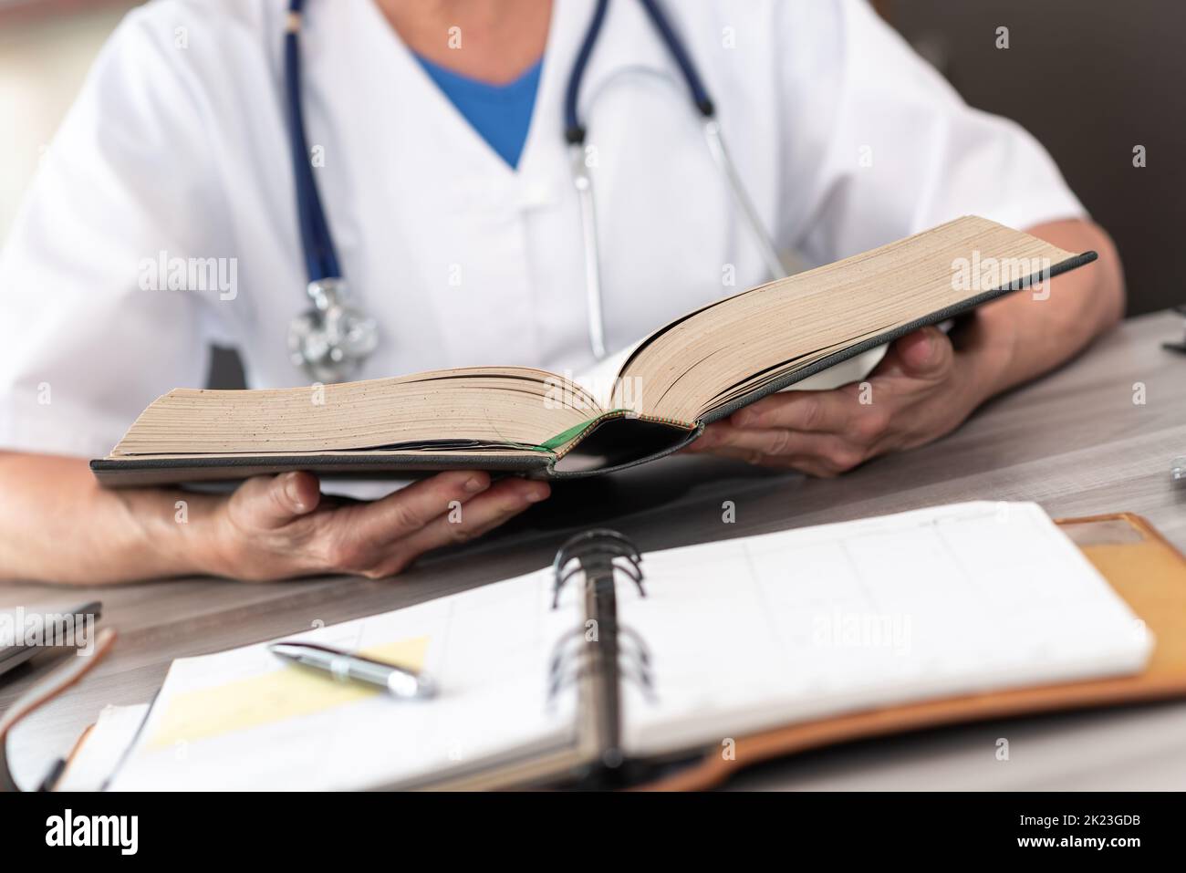 Female doctor reading a textbook in medical office Stock Photo - Alamy