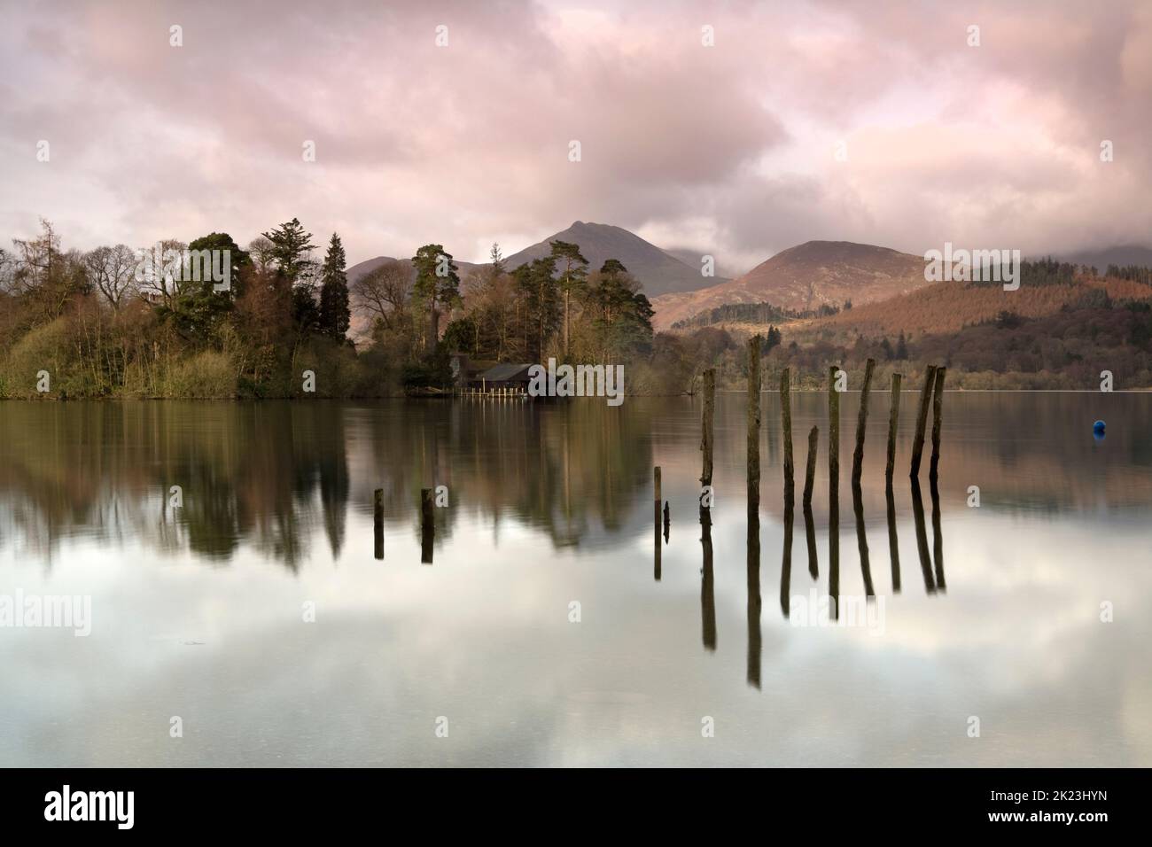 The mountains of the Lake District are reflected in the still water of ...