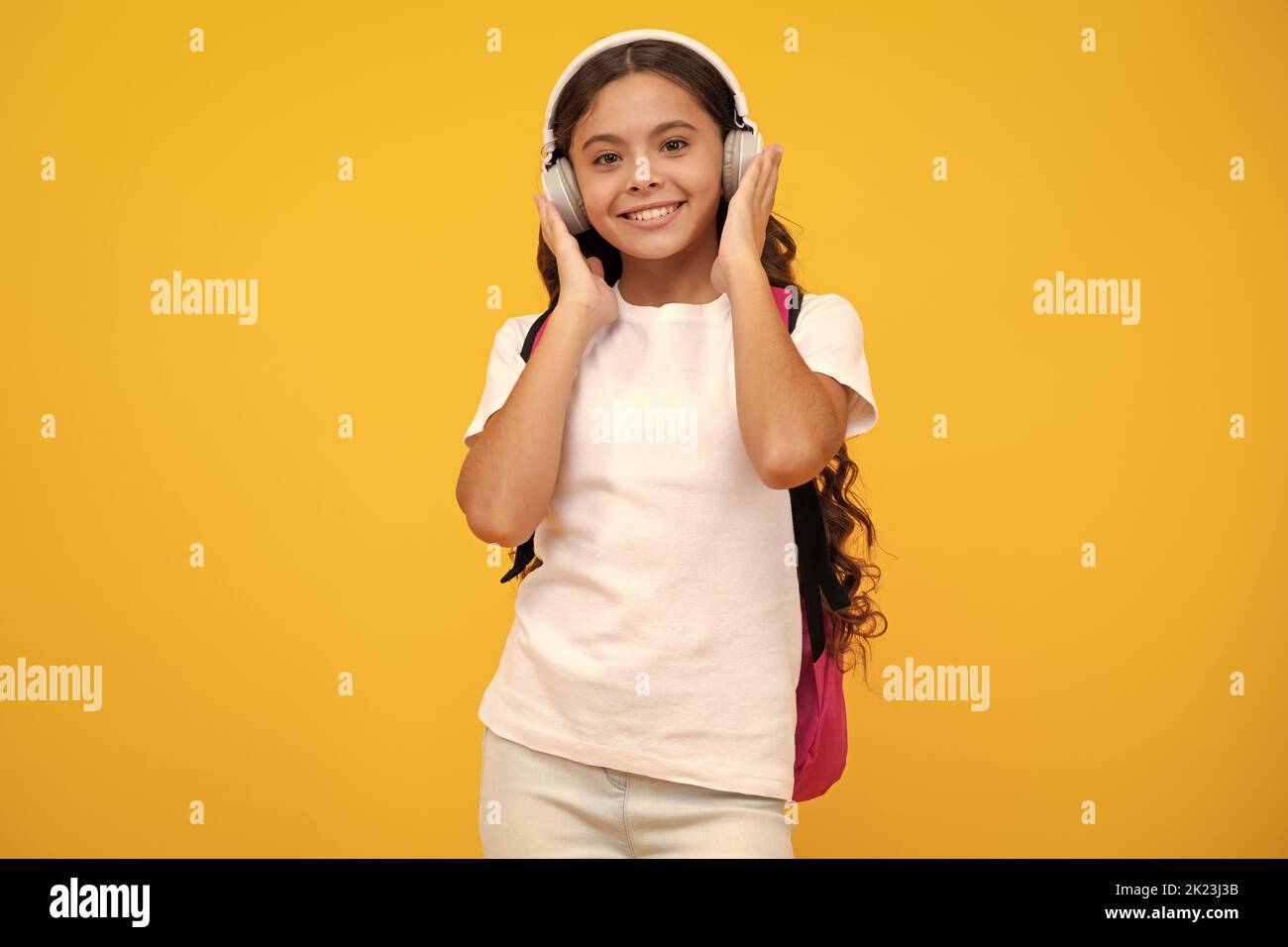 School girl in headphones on isolated studio background. School and ...