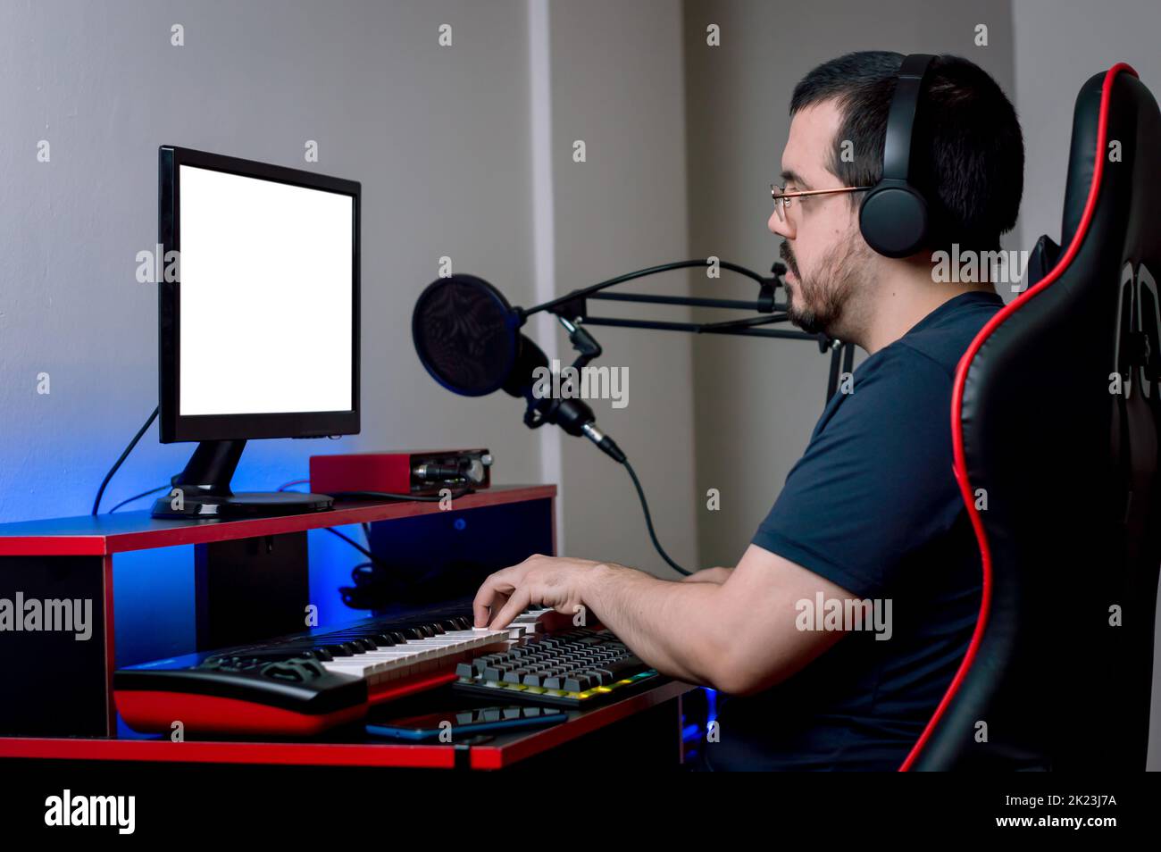side view young latin caucasian man, in his home studio recording music ...