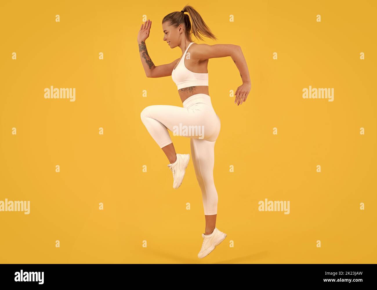 fitness coach woman jumping on yellow background Stock Photo - Alamy
