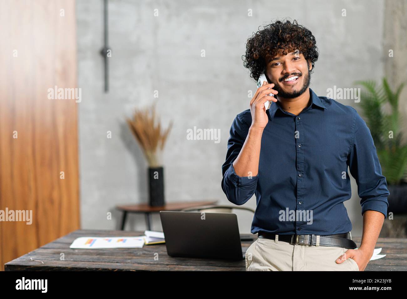 Happy inspired Indian male small business owner talking on the ...