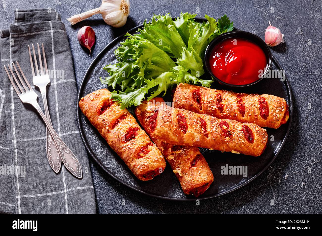 chorizo and semi-dried tomato puff pastry rolls on black plate with ...