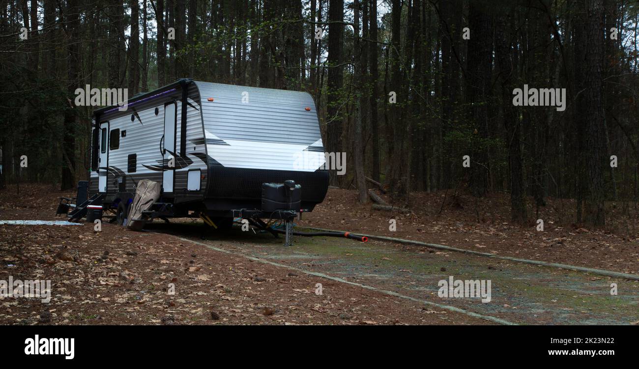 Camping trailer backed into a campsite surrounded by trees Stock Photo ...