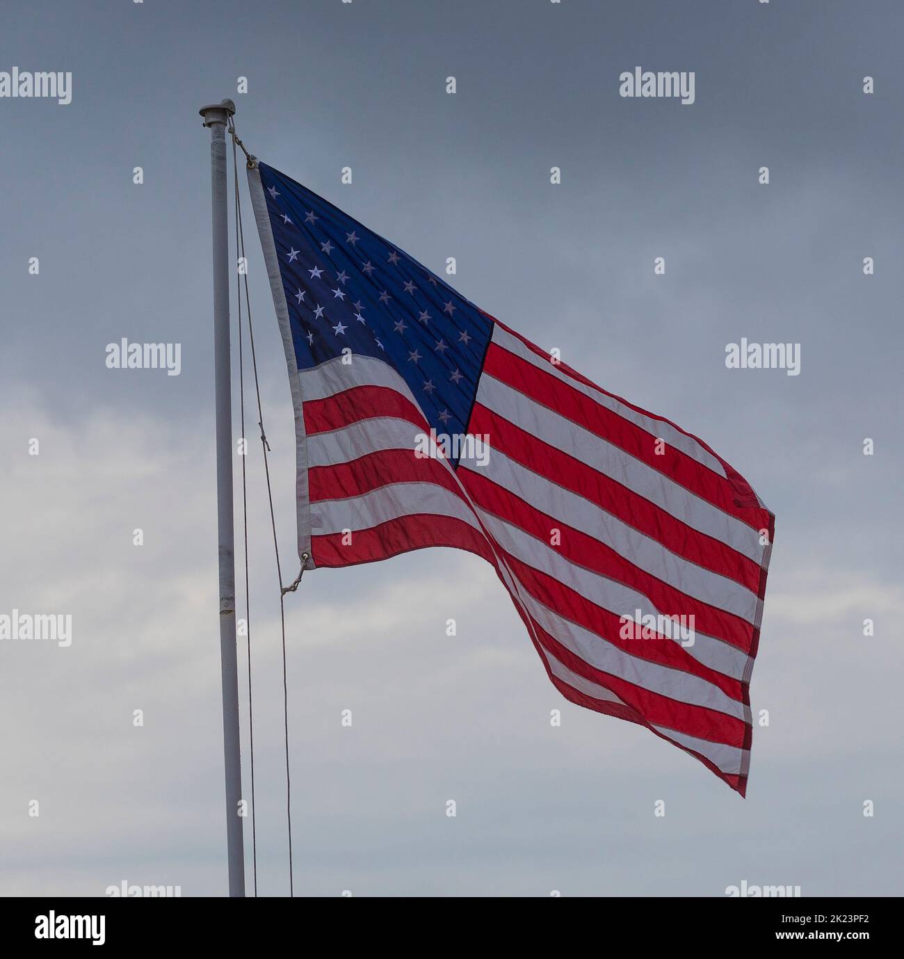 American flag flying on a pole with light clouds behind Stock Photo - Alamy