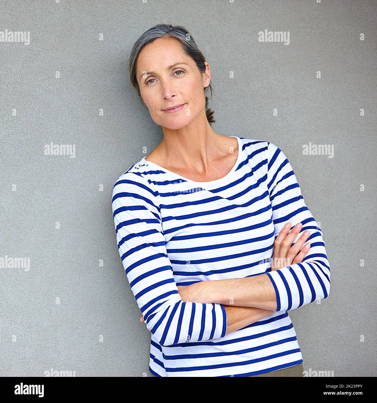 Graceful beauty. Portrait of an attractive mature woman in casualwear standing against a gray ...