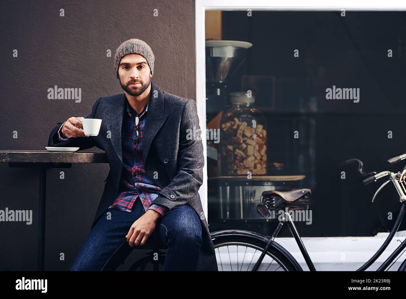 Drinking his coffee in style. Portrait of a handsome young man in ...