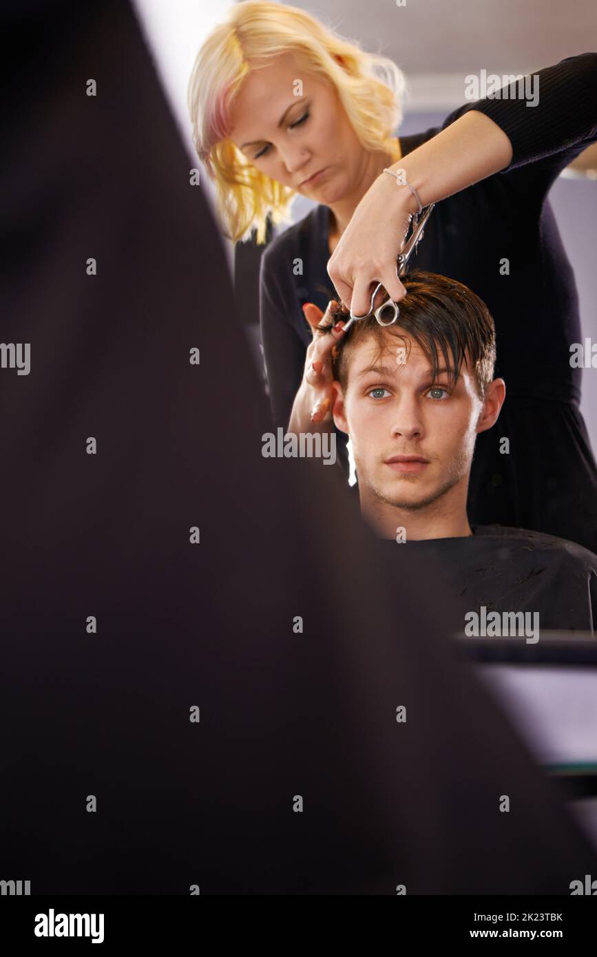 Making sure his hair looks sharp. A young man having his hair styled by ...