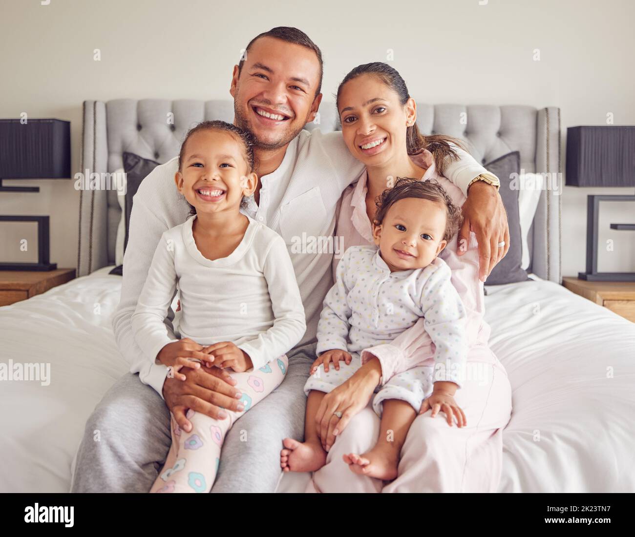 Happy family portrait in bedroom with parents, baby and children smile ...