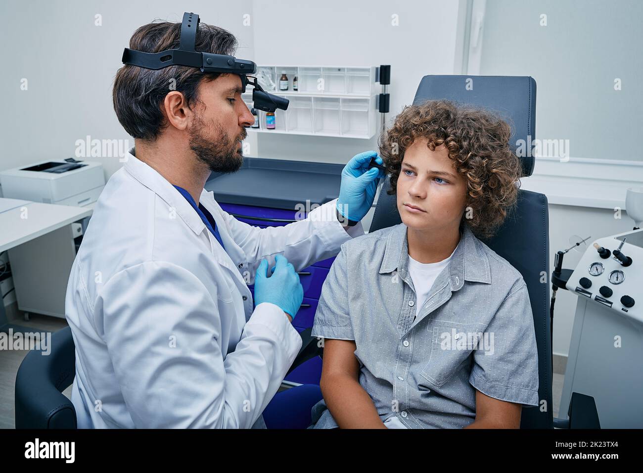 Ear check-up in child, otolaryngology. Curly boy patient during ear ...