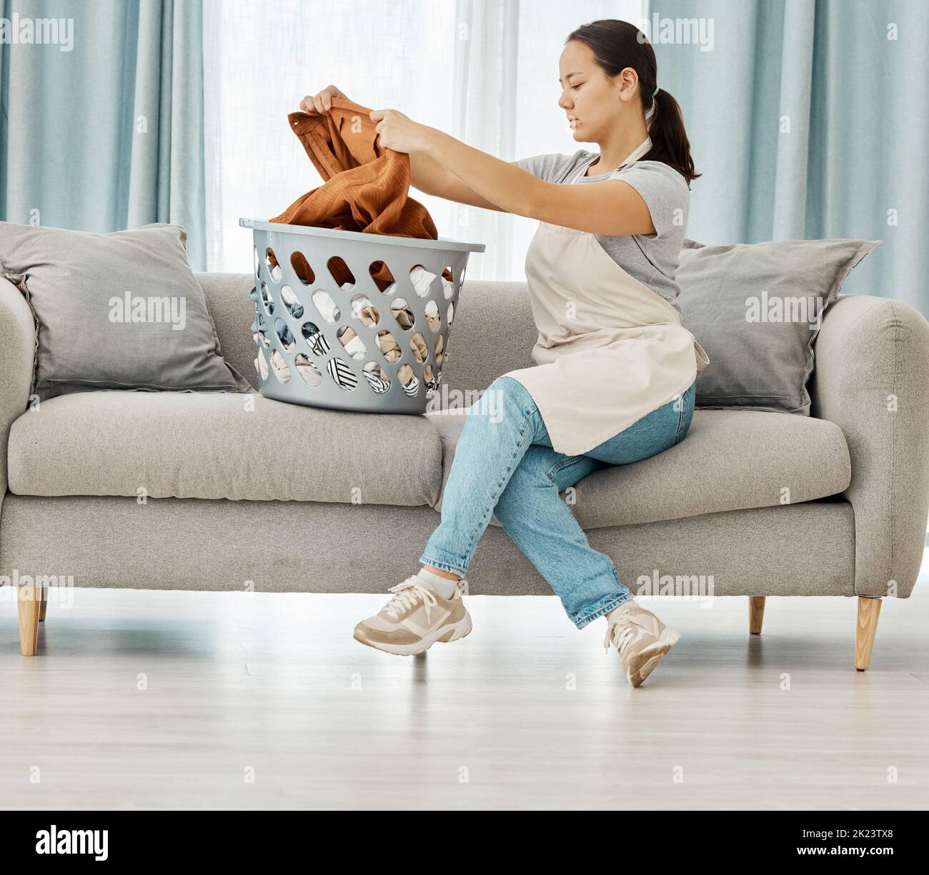 Laundry, basket and cleaning with woman folding clothes on sofa of ...