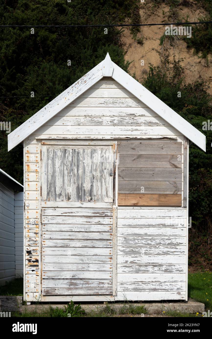 Single white beach hut on the Isle of Wight, England, faded and weathered with rust and paint ...