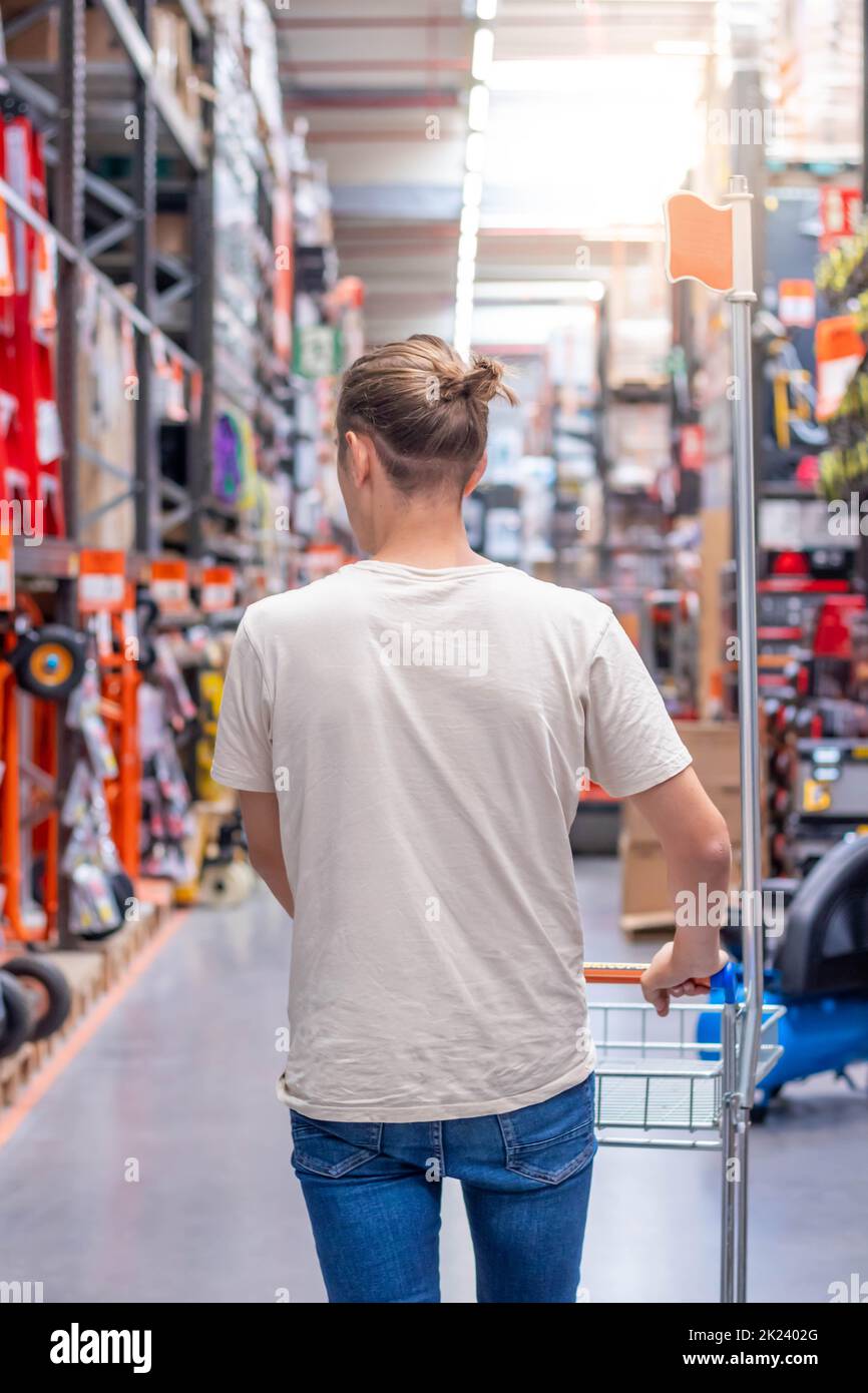 Vertical view of young man from the back carrying a trolley in the ...